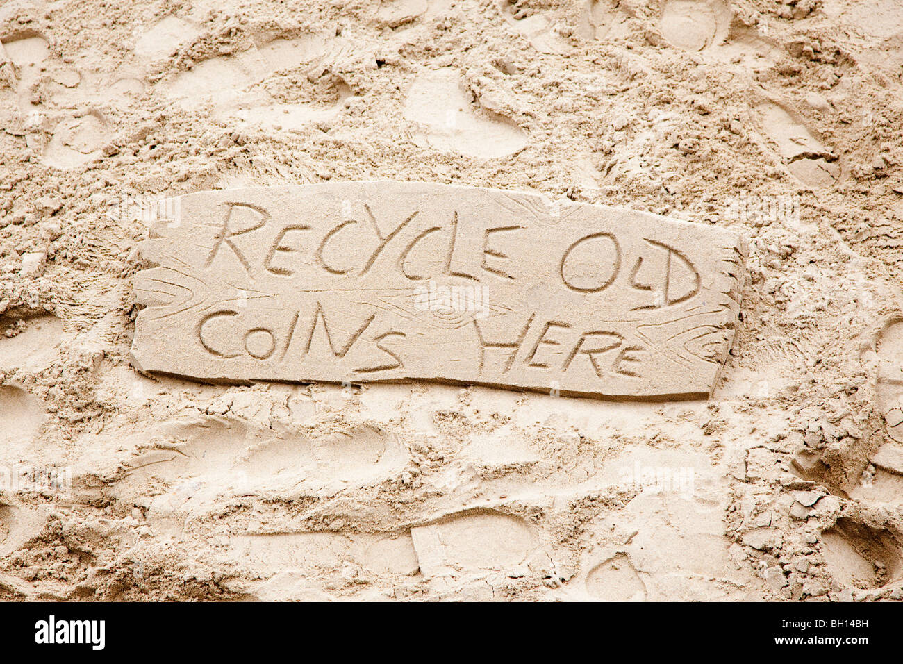 Sand sculpture of a sign asking for money, "Recycle old coins here ...