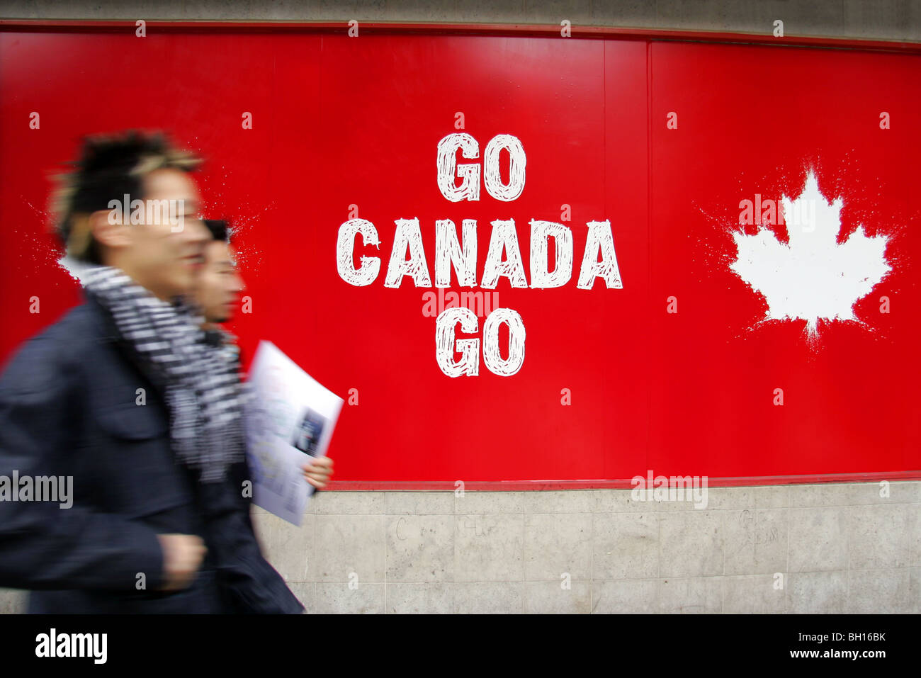 Two asian men walking past a Go Canada Go poster in Vancouver, British ...