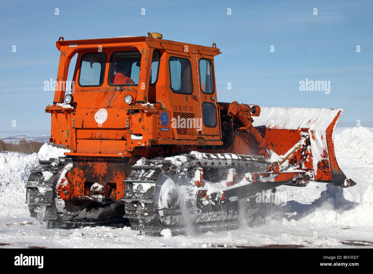 Caterpillar bulldozer pushing deep snow off mountain road in central ...