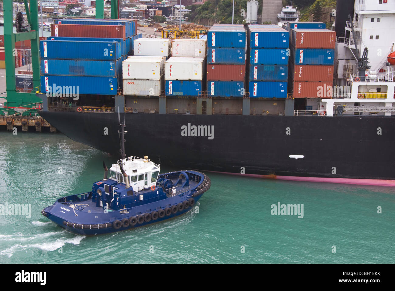 A tug arrives at the stern of a container ship ready to assist the ship ...