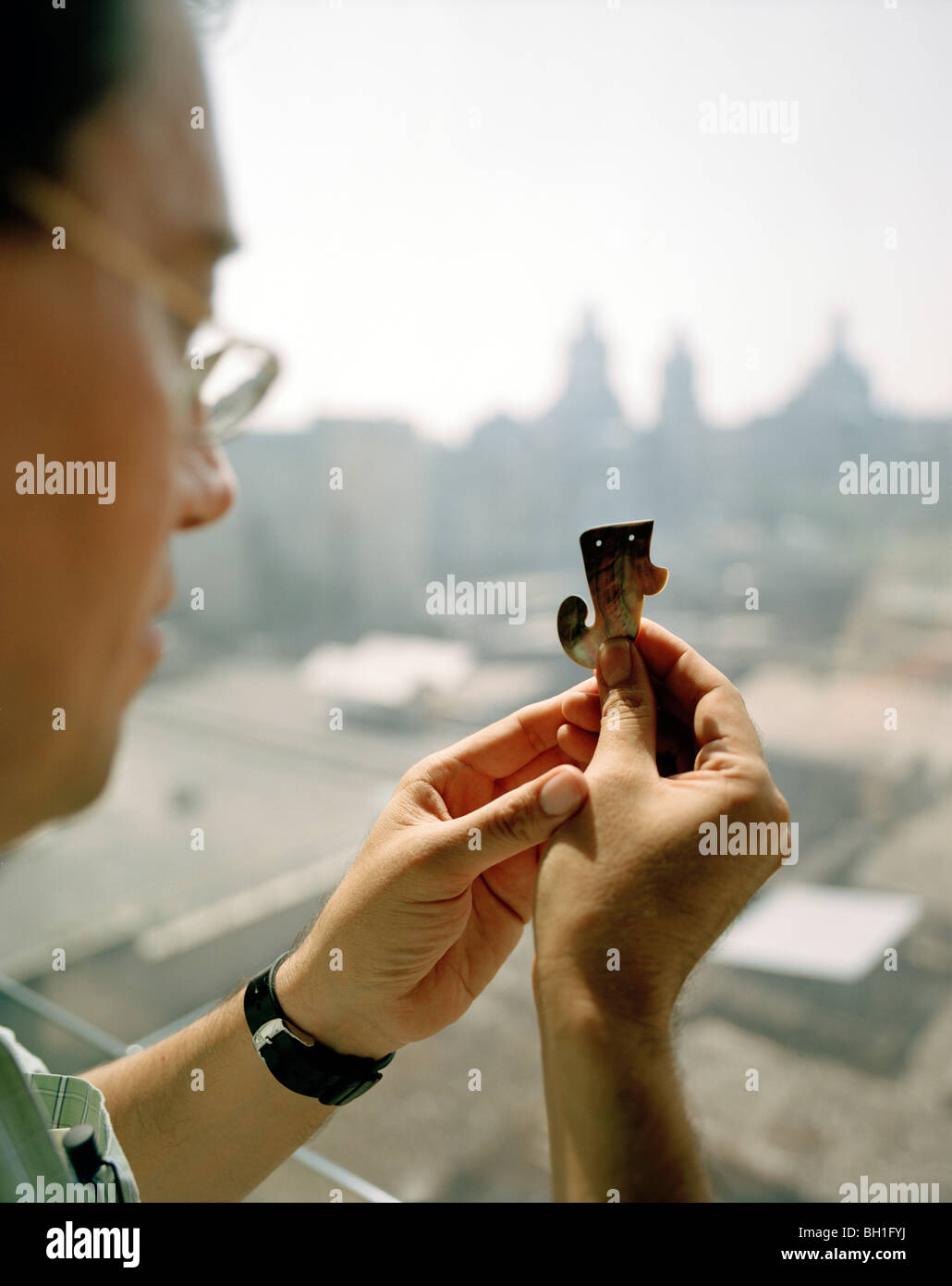 Archaeologist A. Velasquez Castro looking at Aztec hook made of mother ...