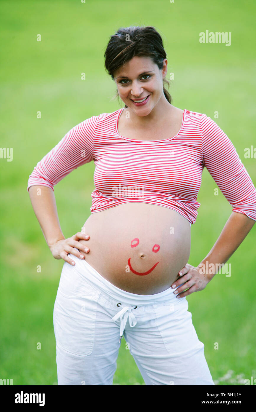 Pregnant woman with smiley face on belly Stock Photo - Alamy