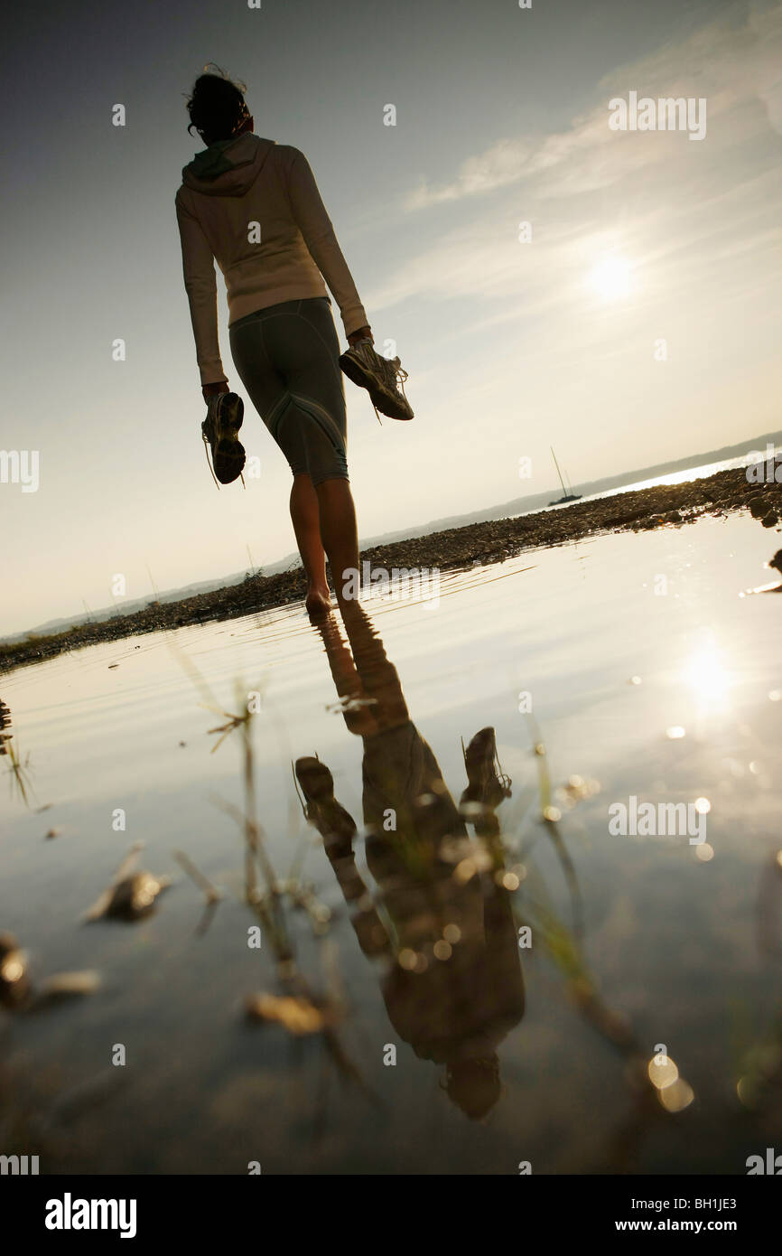 Barefoot female jogger standing at lake Starnberg, Ambach, Bavaria ...