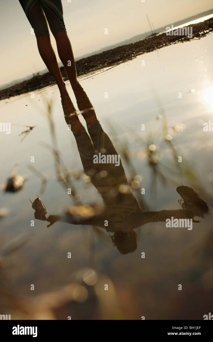 Barefoot female jogger standing at lake Starnberg, Ambach, Bavaria ...