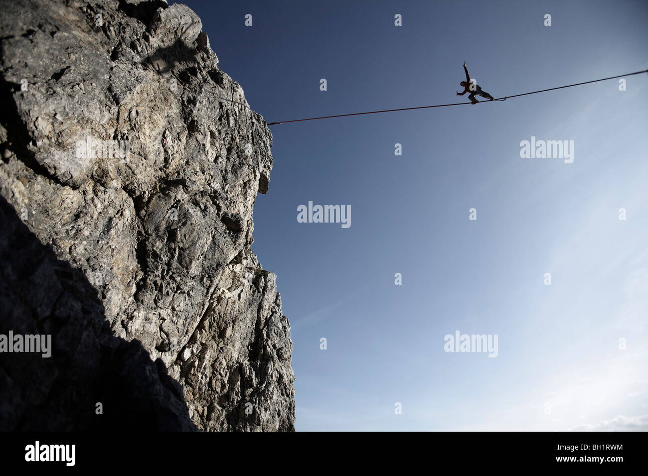 Man balancing on a rope over an abyss, slackline in the mountains ...