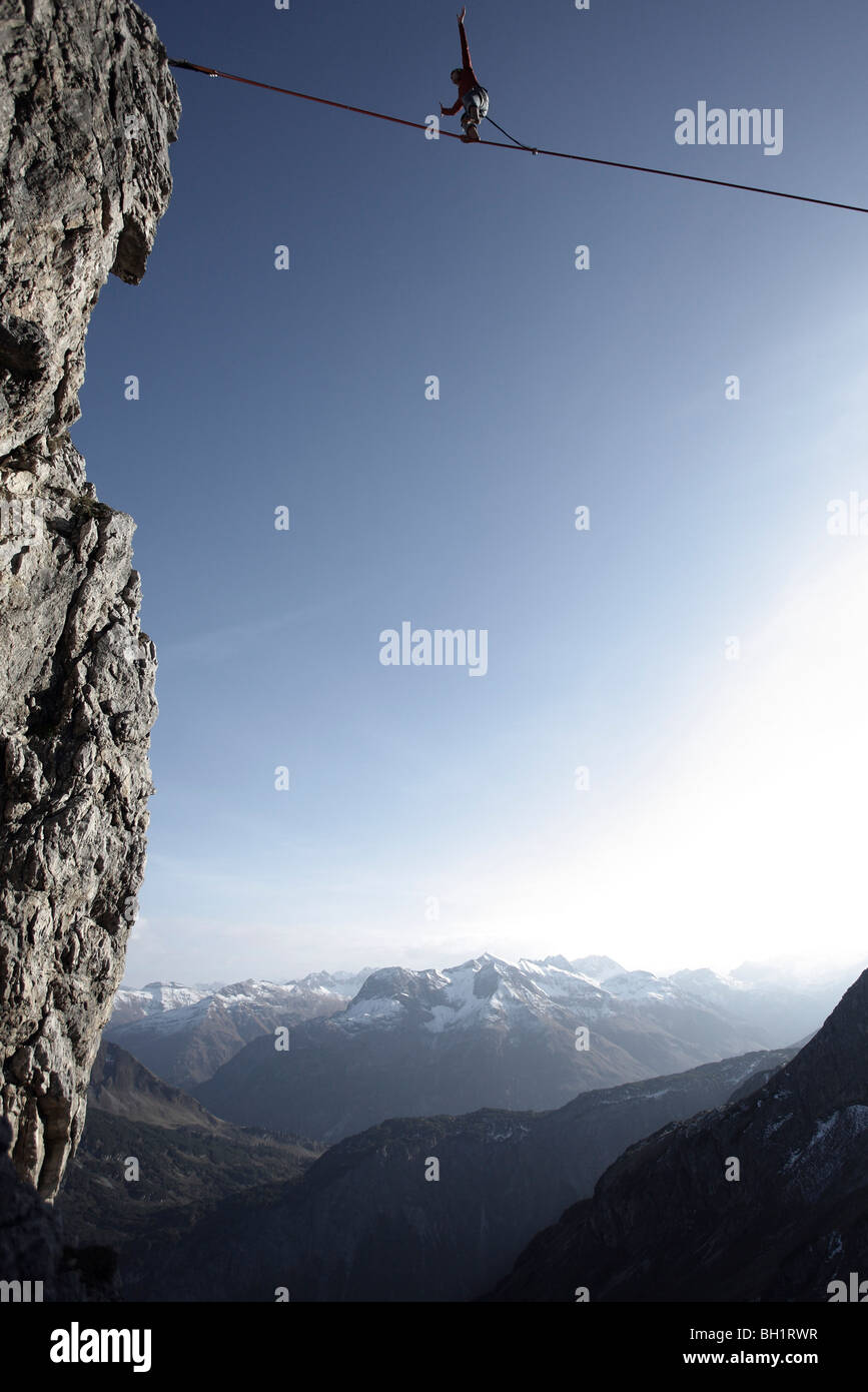Man balancing on a rope over an abyss, slackline in the mountains ...