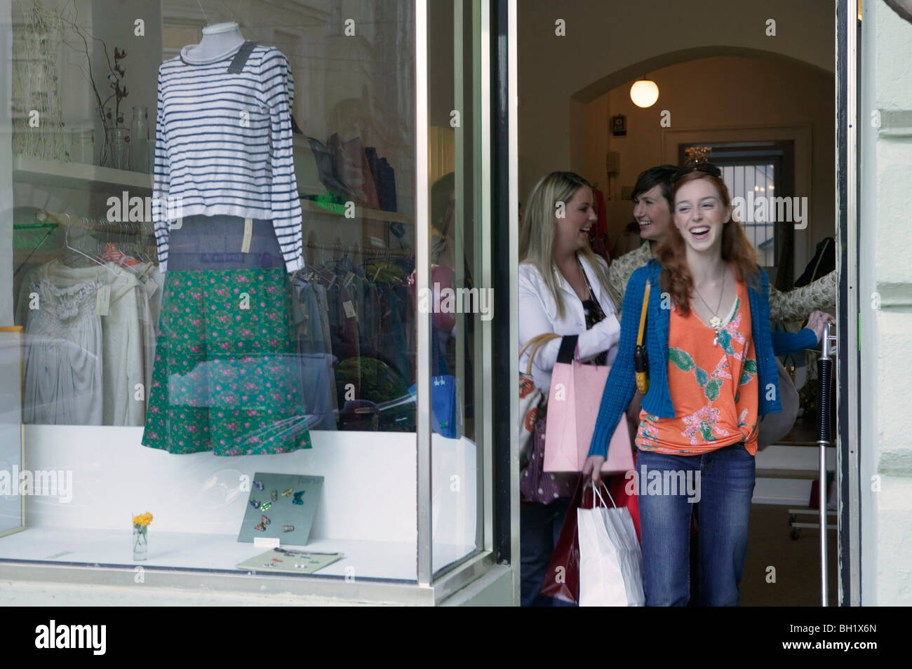 Young women walking out of shop with shopping bags Stock Photo - Alamy