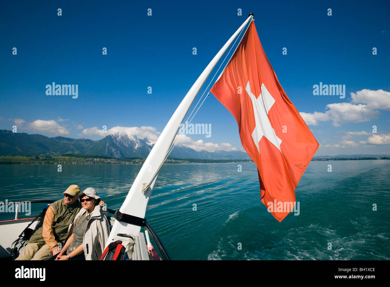 Couple sitting at stern of a ship, swiss flag blowing in the wind, Lake ...