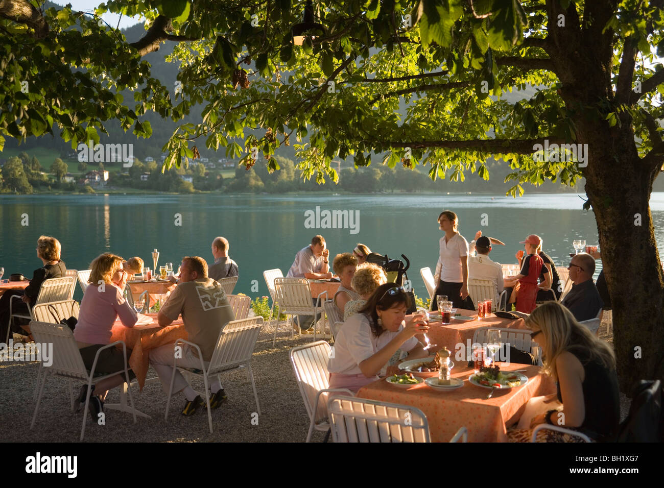 People sitting in the open air area of a restaurant at Lake Fuschl in ...