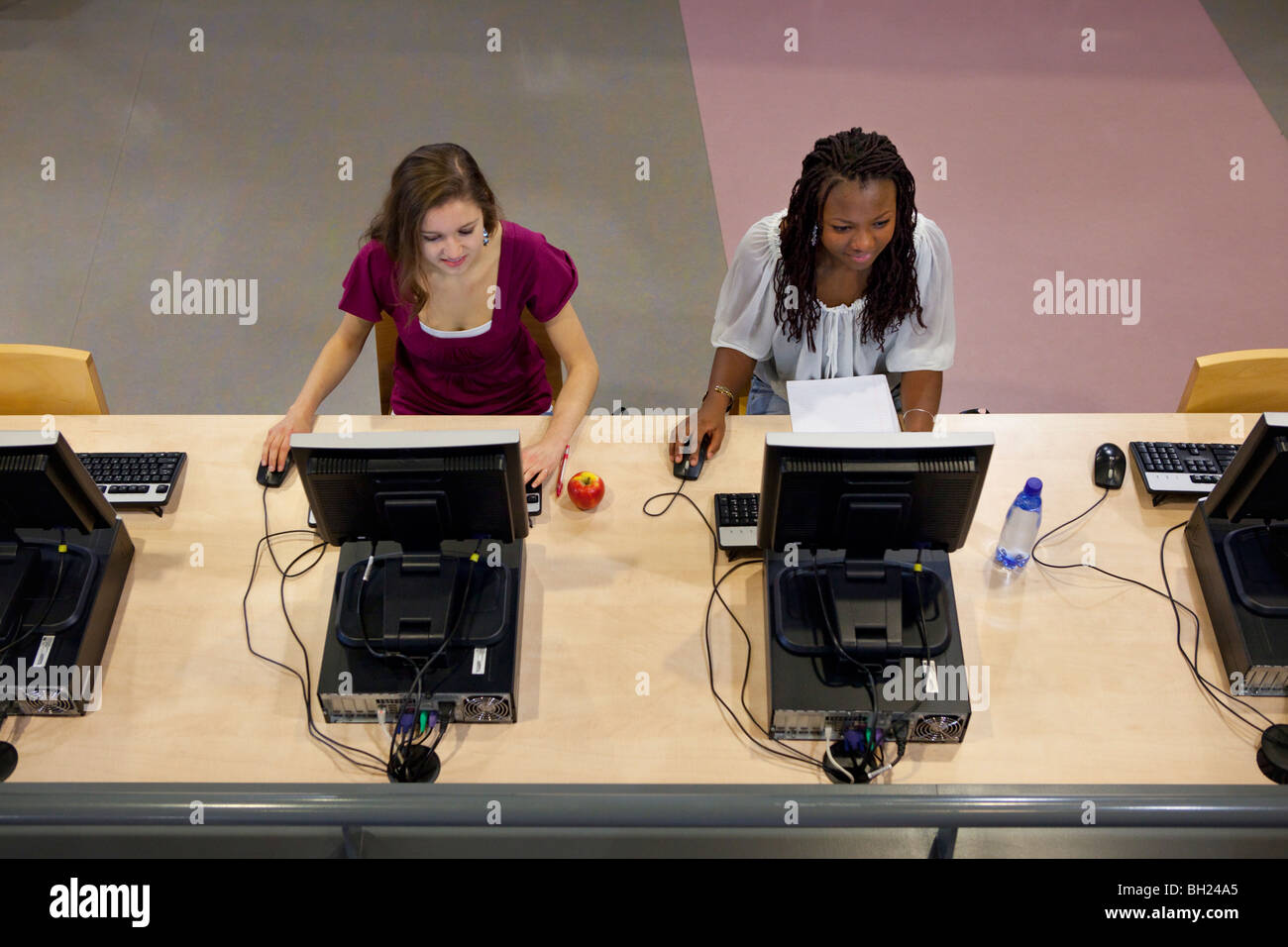 Two teenage girls in the library behind a computer Stock Photo - Alamy