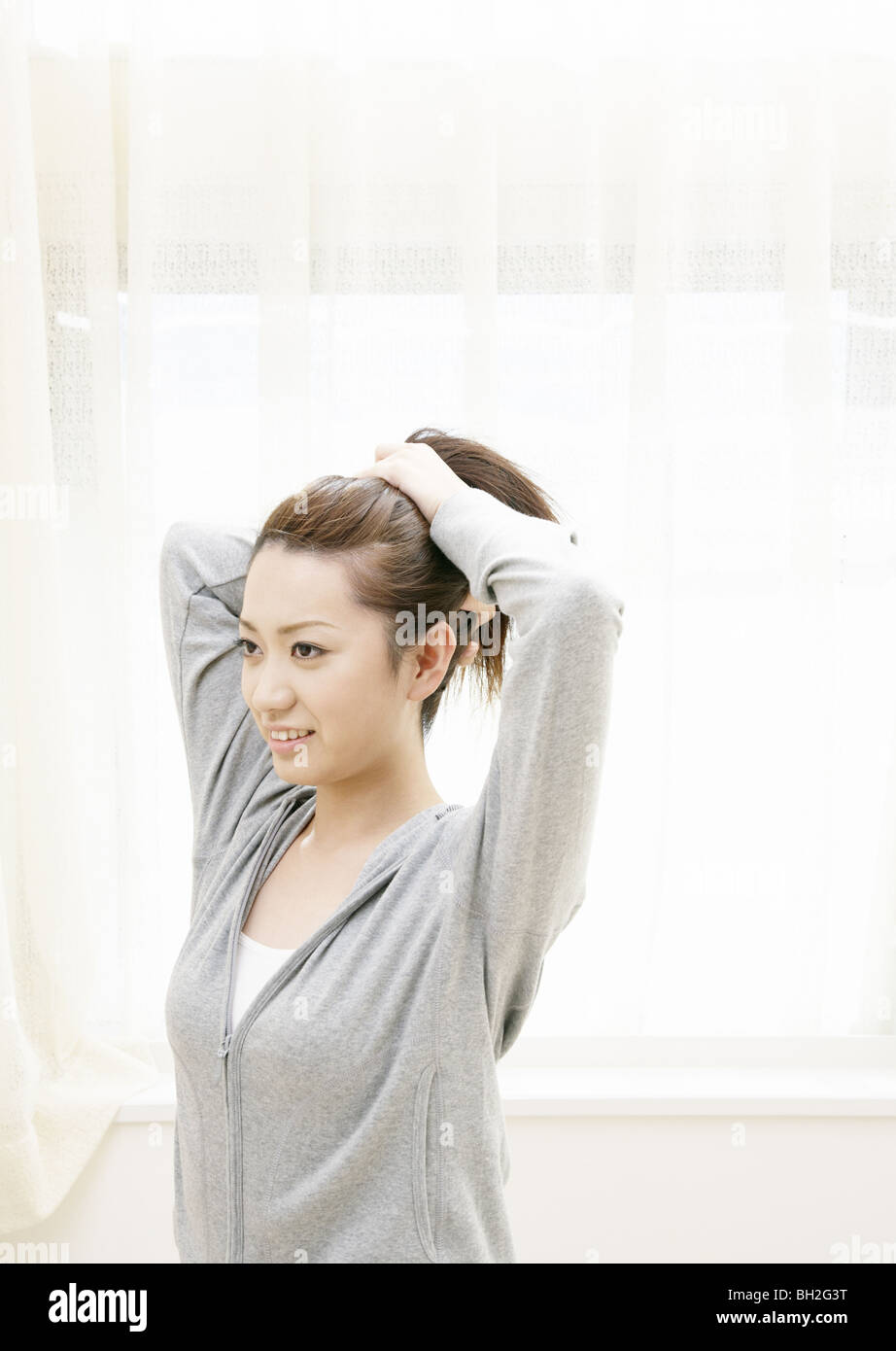 A young woman fixing her hair Stock Photo - Alamy