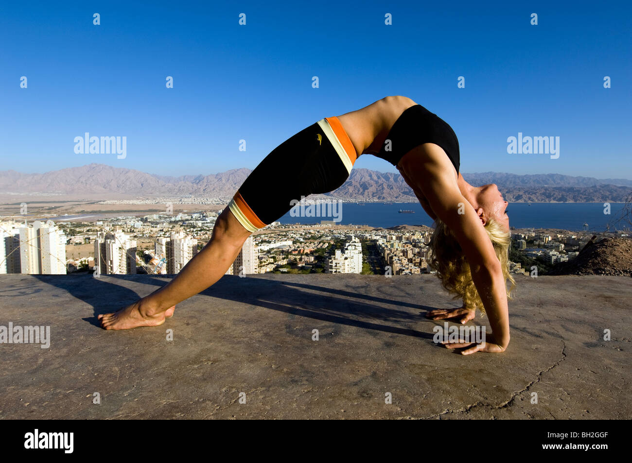 Young European woman performs outdoors a series of Yoga exercises on ...