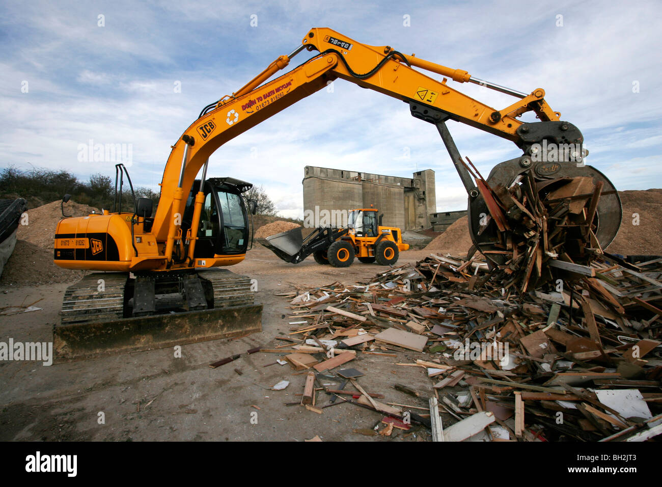 A JCB digger loading recycled wood into a chipper Stock Photo - Alamy