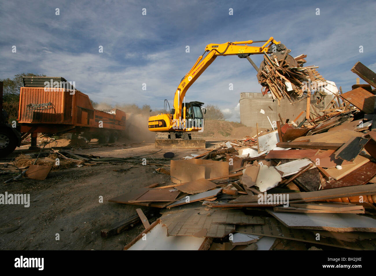 A JCB digger loading recycled wood into a chipper Stock Photo - Alamy