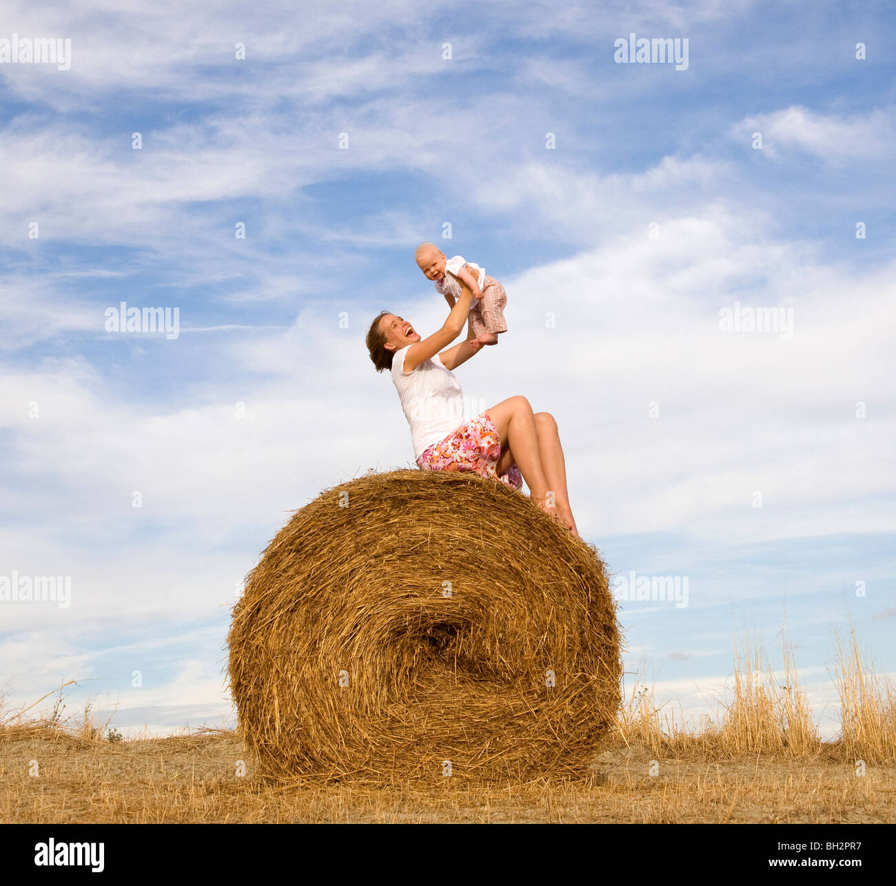 Two young women lifting hay bales in a barn Stock Photo - Alamy