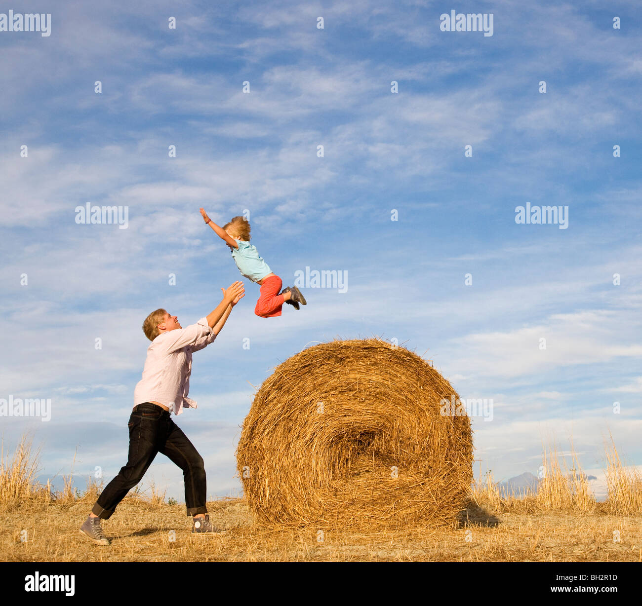 man catching boy jumping from hay bale Stock Photo - Alamy