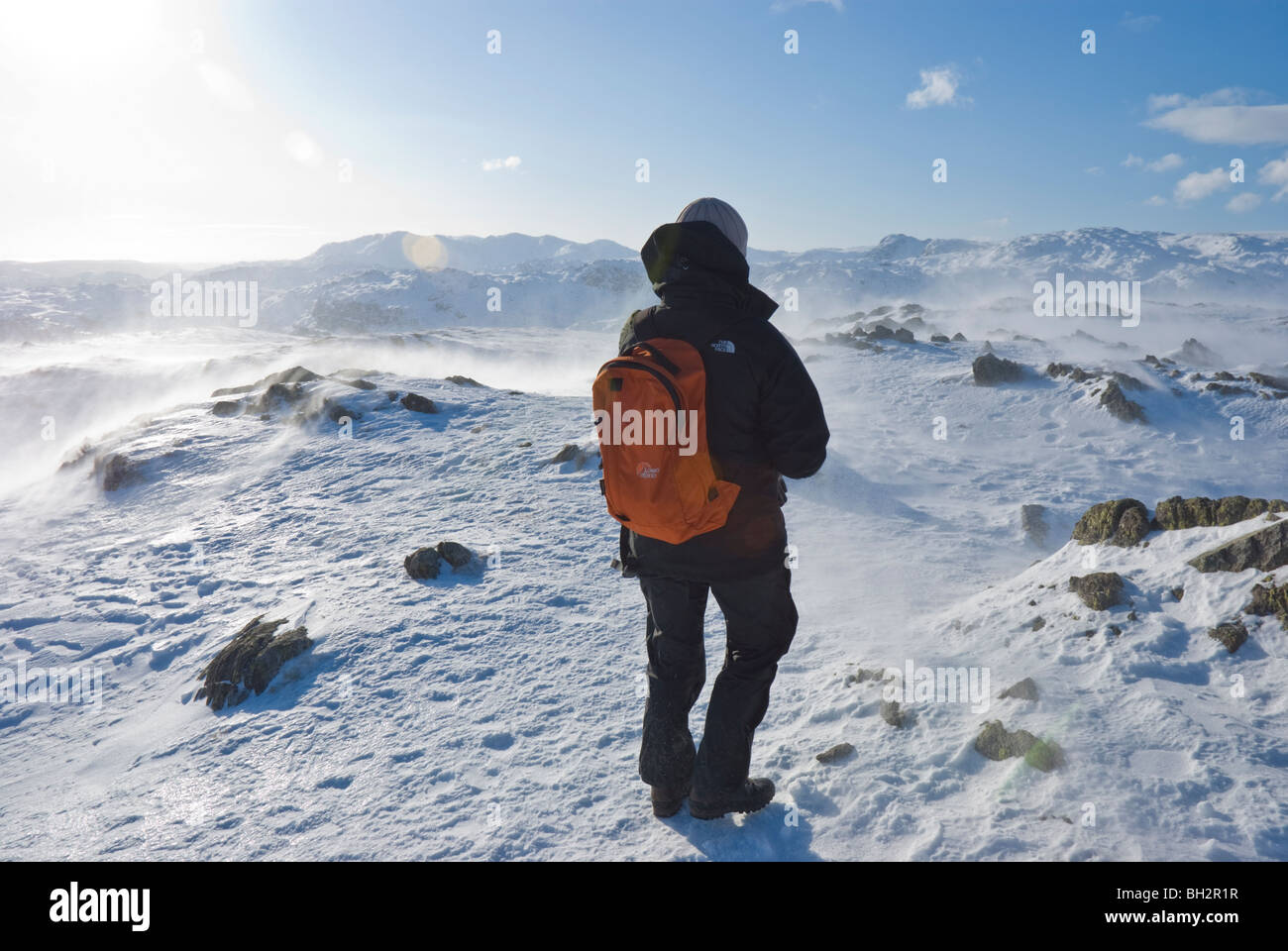 Lone female walker with winter clothing and rucksack on top of snow ...
