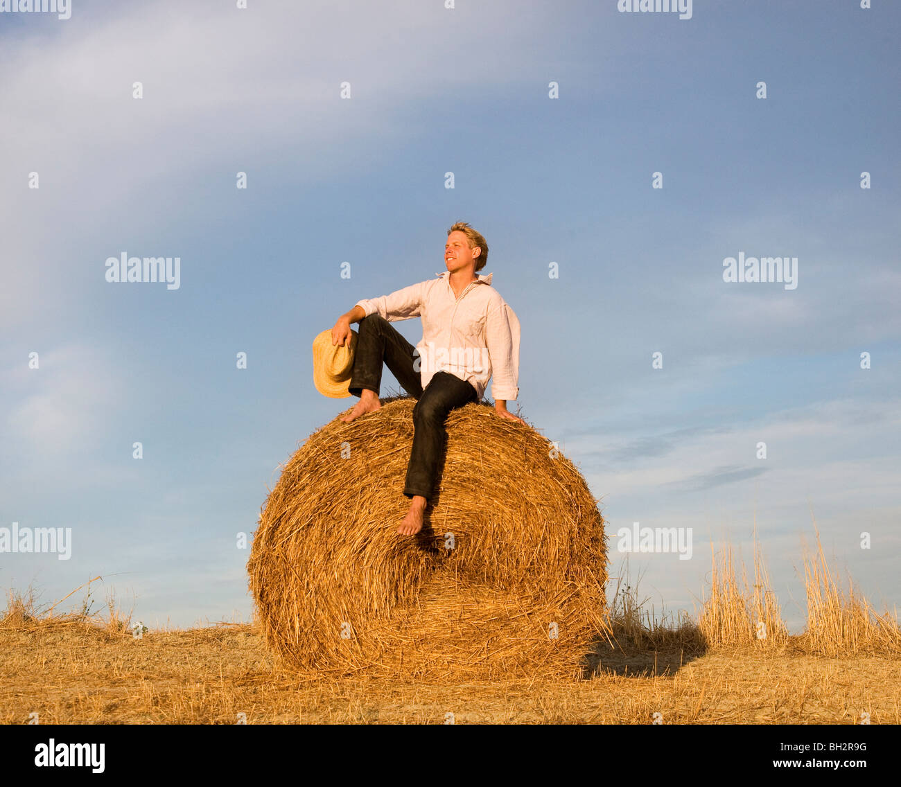 man sitting on hay bale Stock Photo - Alamy