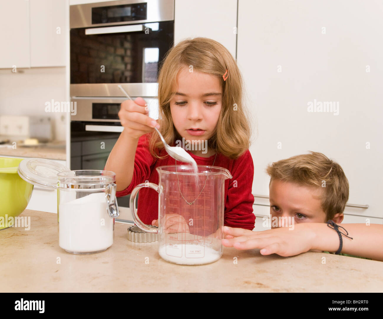 girl and boy measuring sugar Stock Photo - Alamy