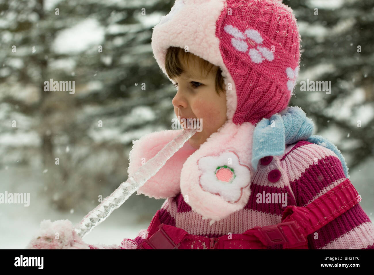 Cute little girl eating an icicle Stock Photo - Alamy