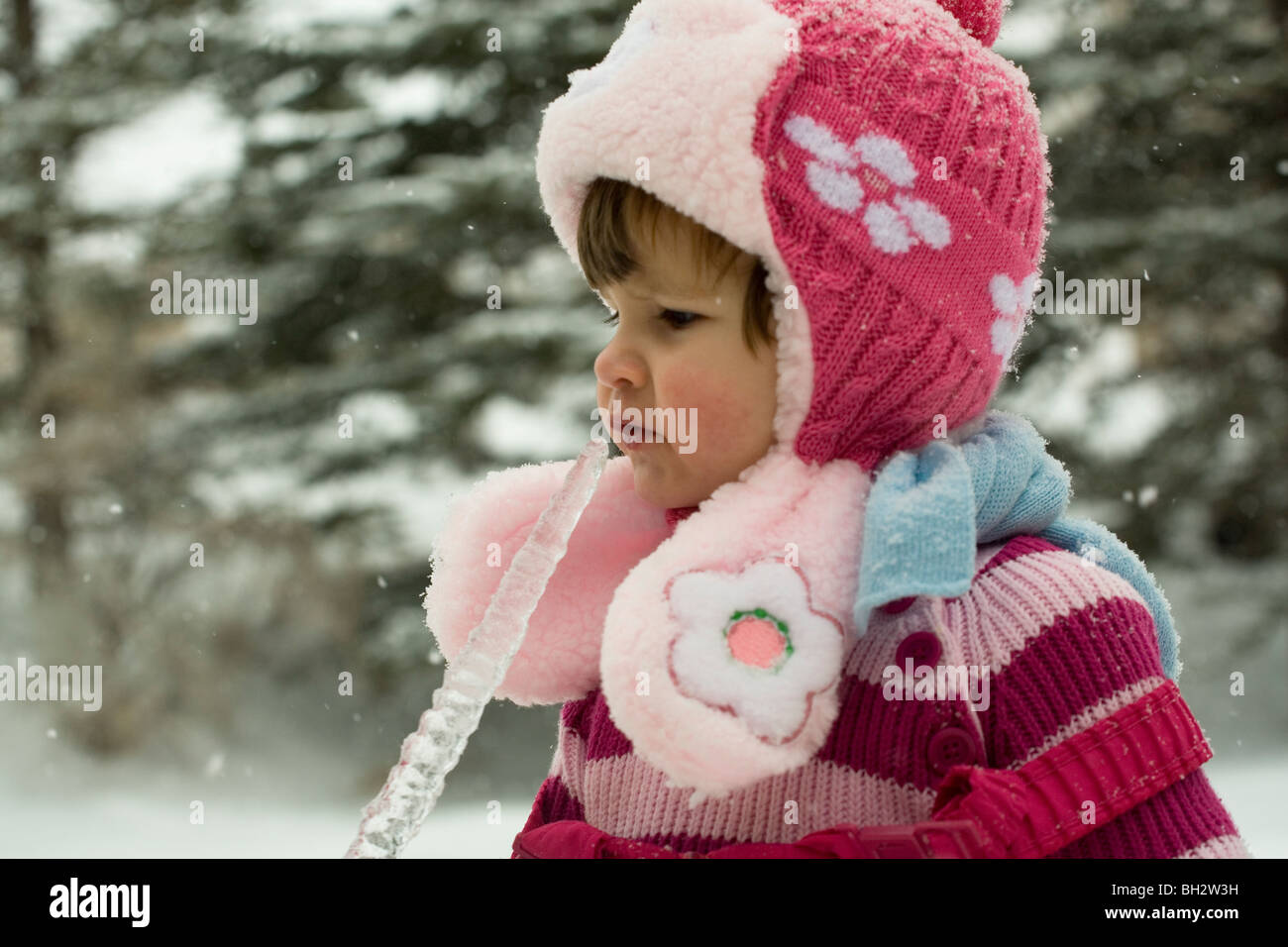 Cute little girl eating an icicle Stock Photo - Alamy