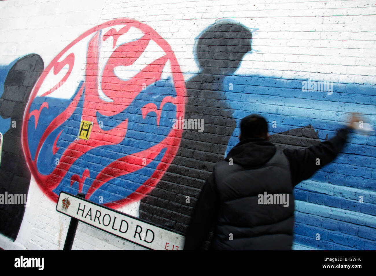 Graffiti artist Mohammed Ali spray painting a mural onto a wall in ...