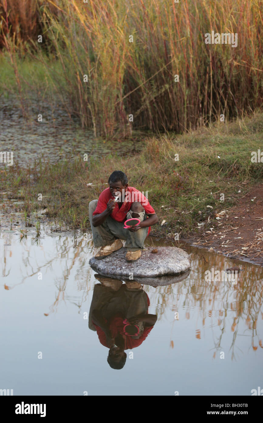 Using a hand mirror, an Angolan local brushes his teeth in the Longa ...