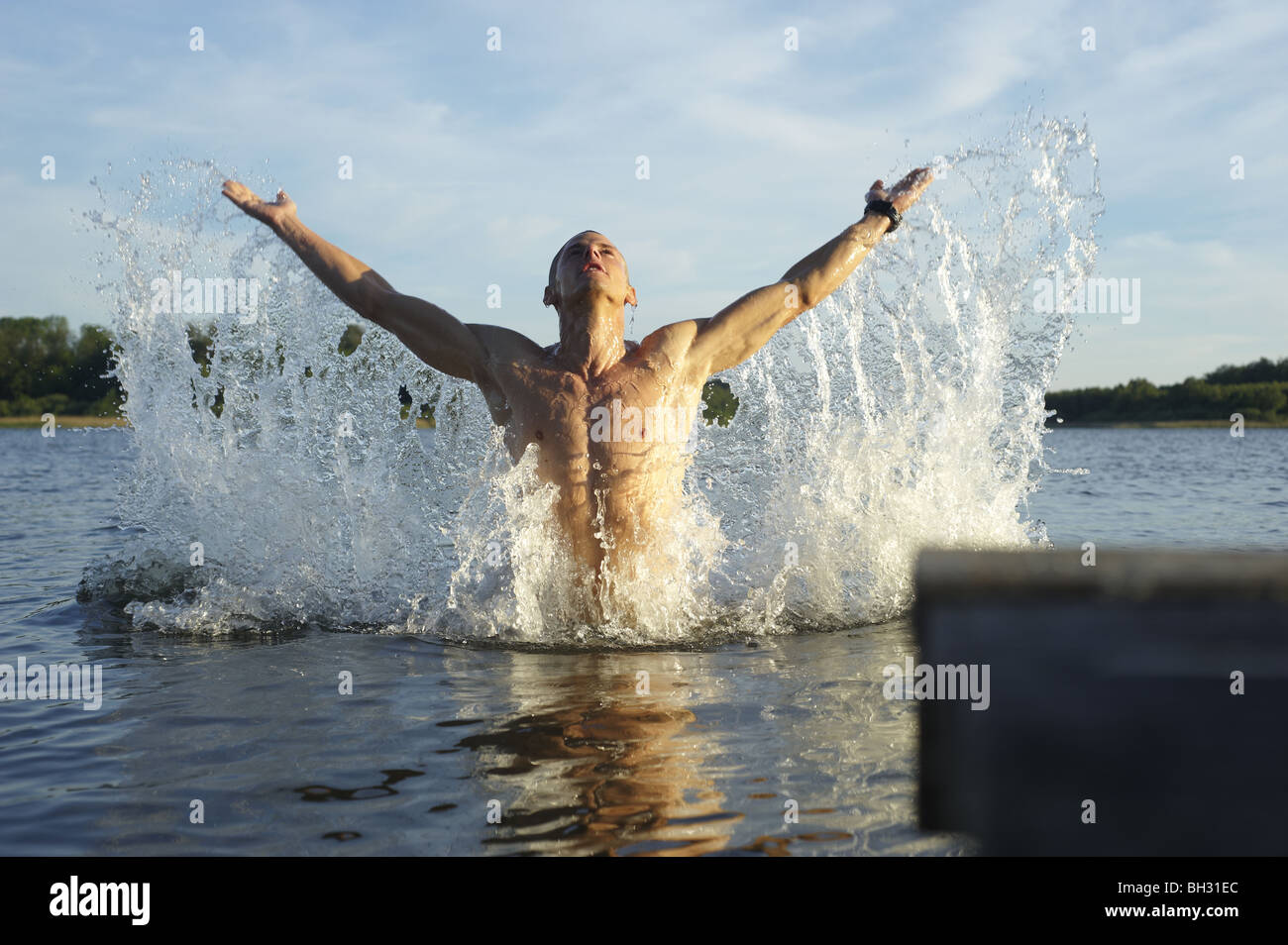 Young man in water causing large upward splash Stock Photo - Alamy
