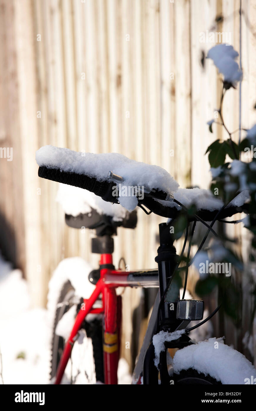 a bicycle left in the snow against a fence Stock Photo - Alamy