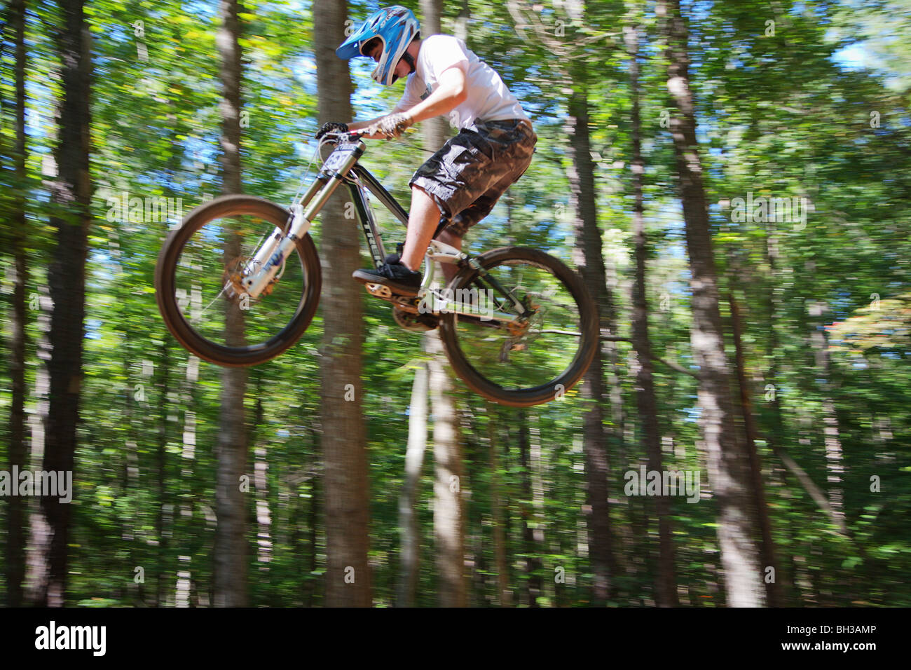 MOUNTAIN BIKER ON BICYCLE LEAPING OVER A JUMP AND PERFORMING A TRICK ...
