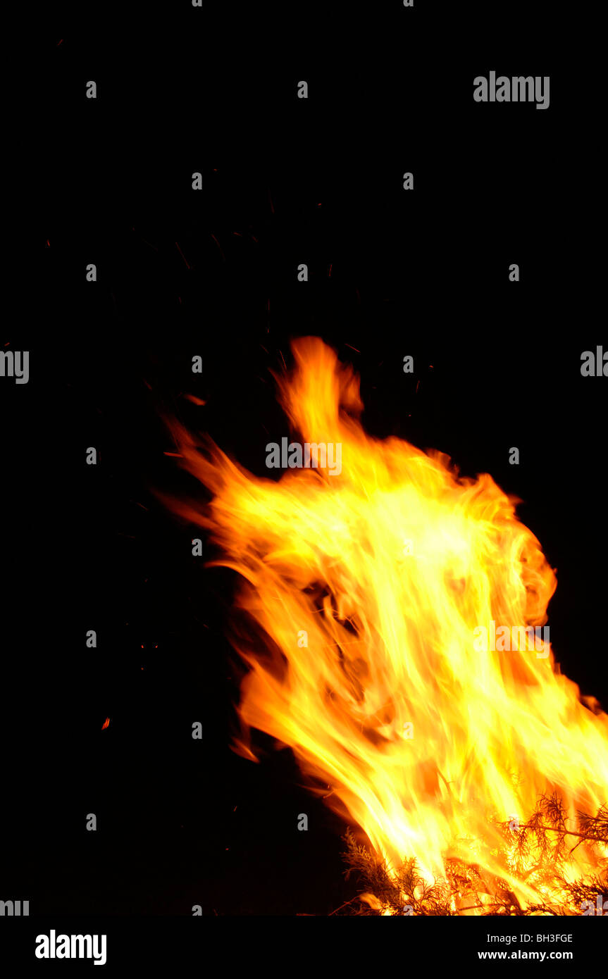 Flames of a outdoor campfire flare up, dance and surge for a ...