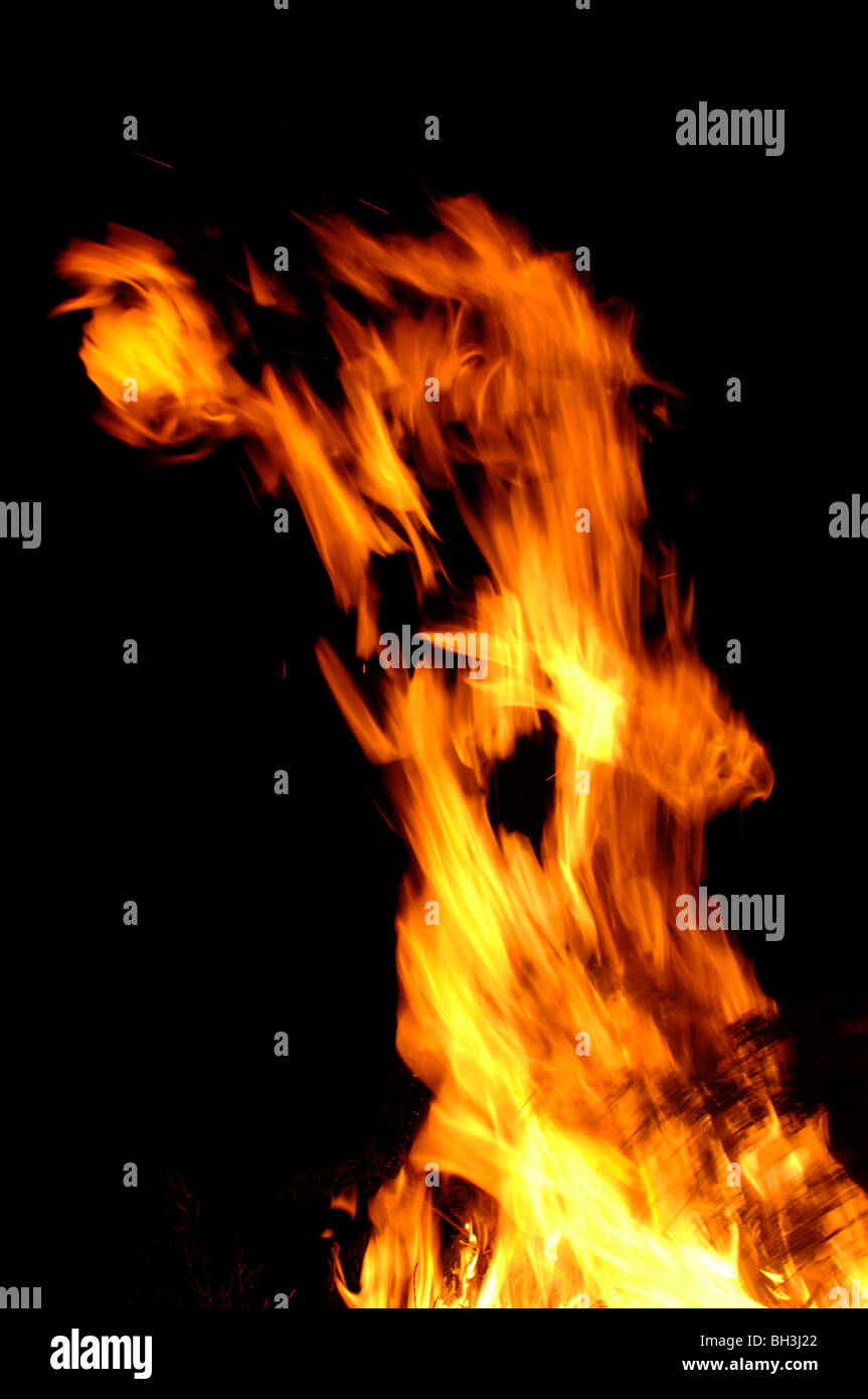 Flames of a outdoor campfire flare up, dance and surge for a ...