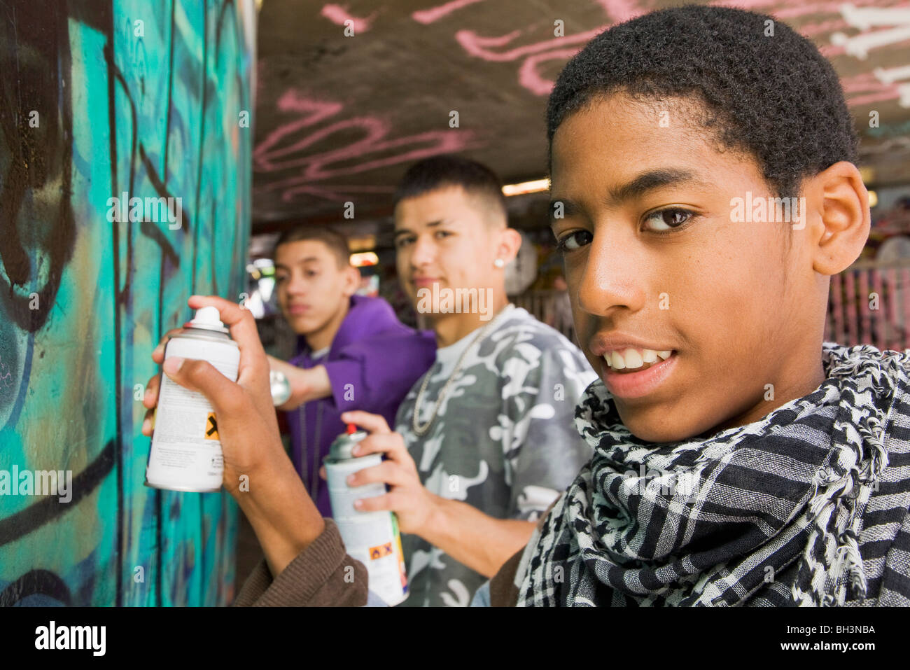 Teenage gang doing graffiti on a wall Stock Photo - Alamy