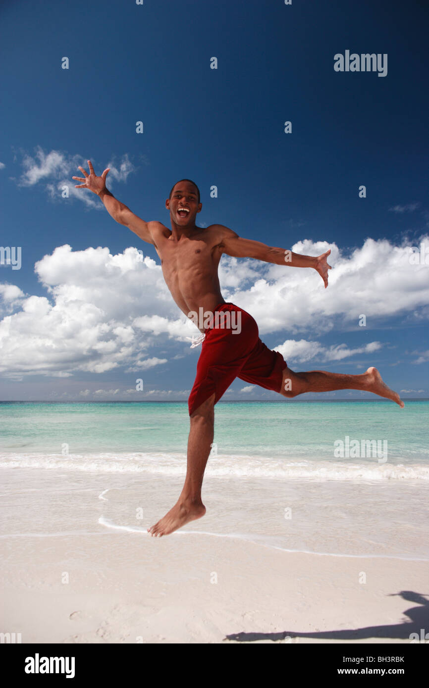 Young man leaping on a tropical beach, smiling Stock Photo - Alamy