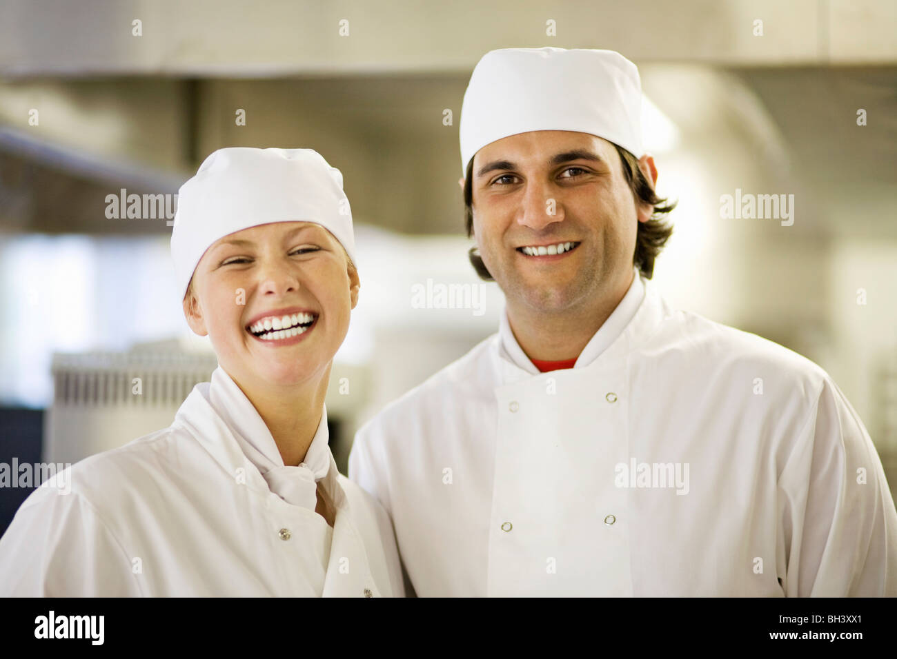Two chefs in a kitchen smiling Stock Photo - Alamy