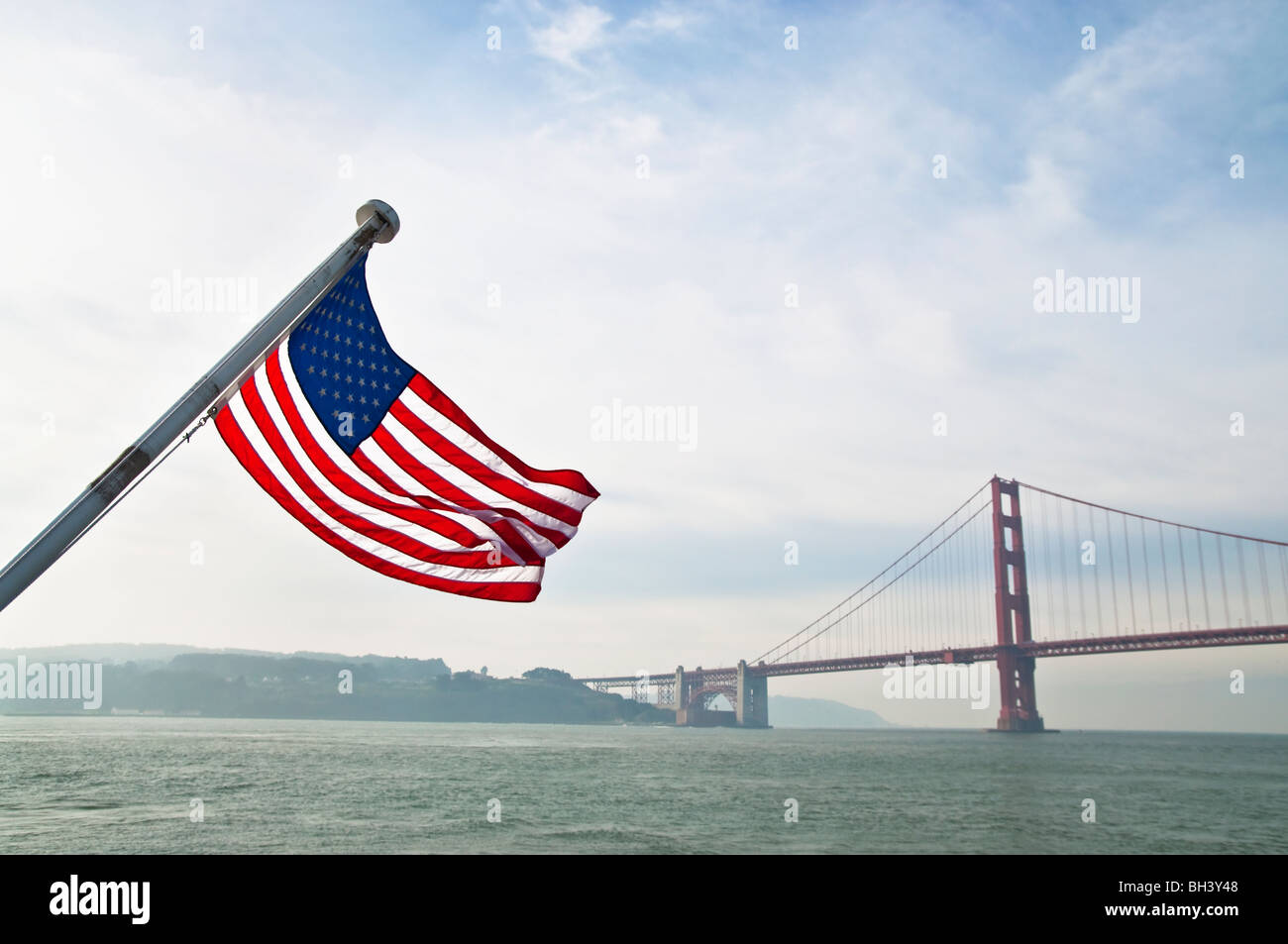 The American flag waving gloriously with the Golden Gate Bridge in the ...