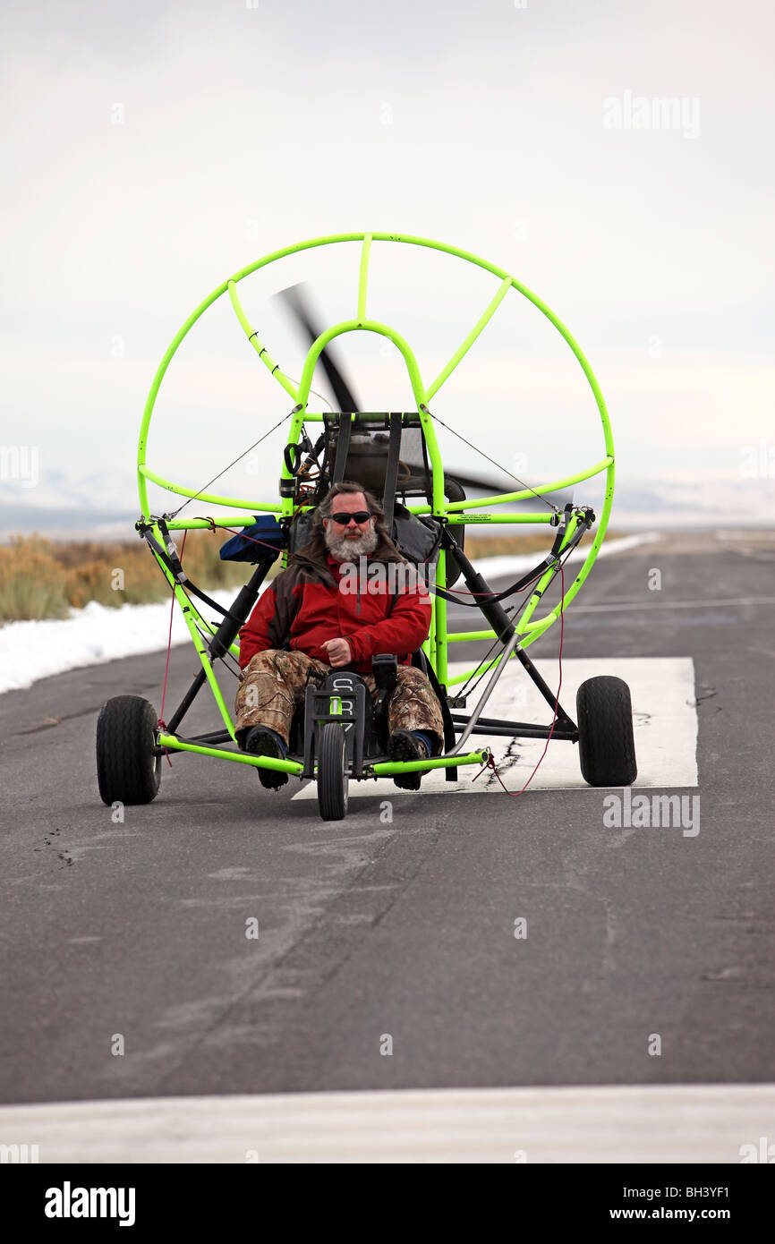 Pilot sitting in a powered parachute on the runway with engine running ...