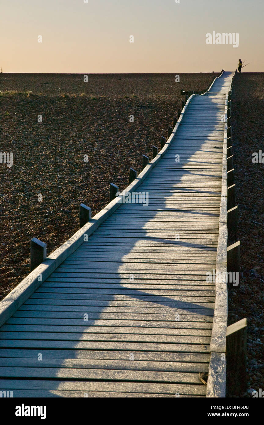 Frost covered walkway on Dungeness beach with long dawn shadows and ...