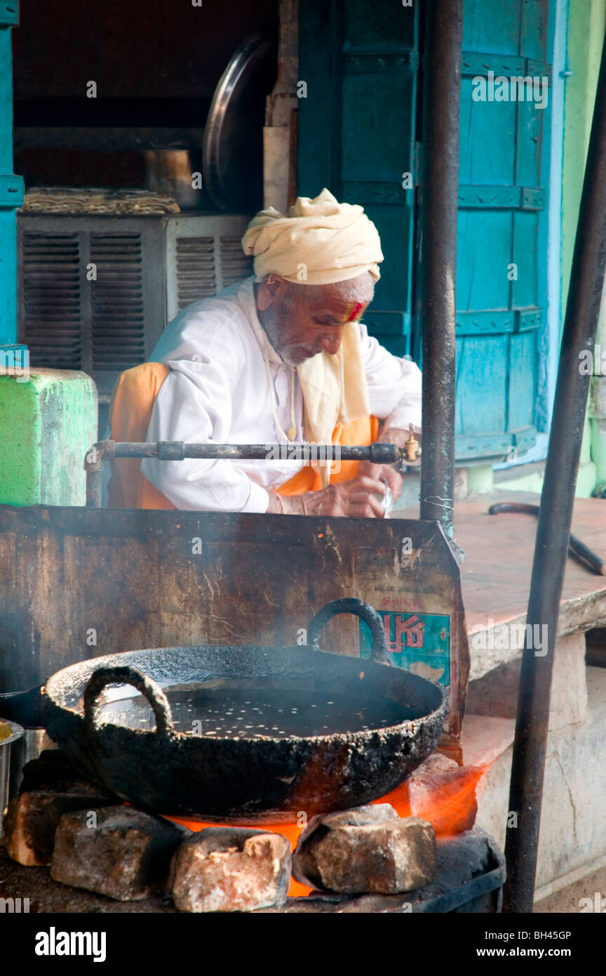Religious man cleaning cup next to cooking pot Stock Photo - Alamy