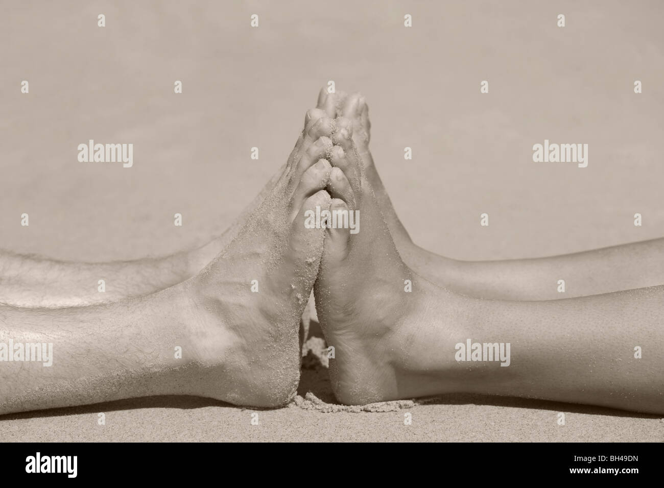 A man and a woman pressing their feet against each other lying on a ...