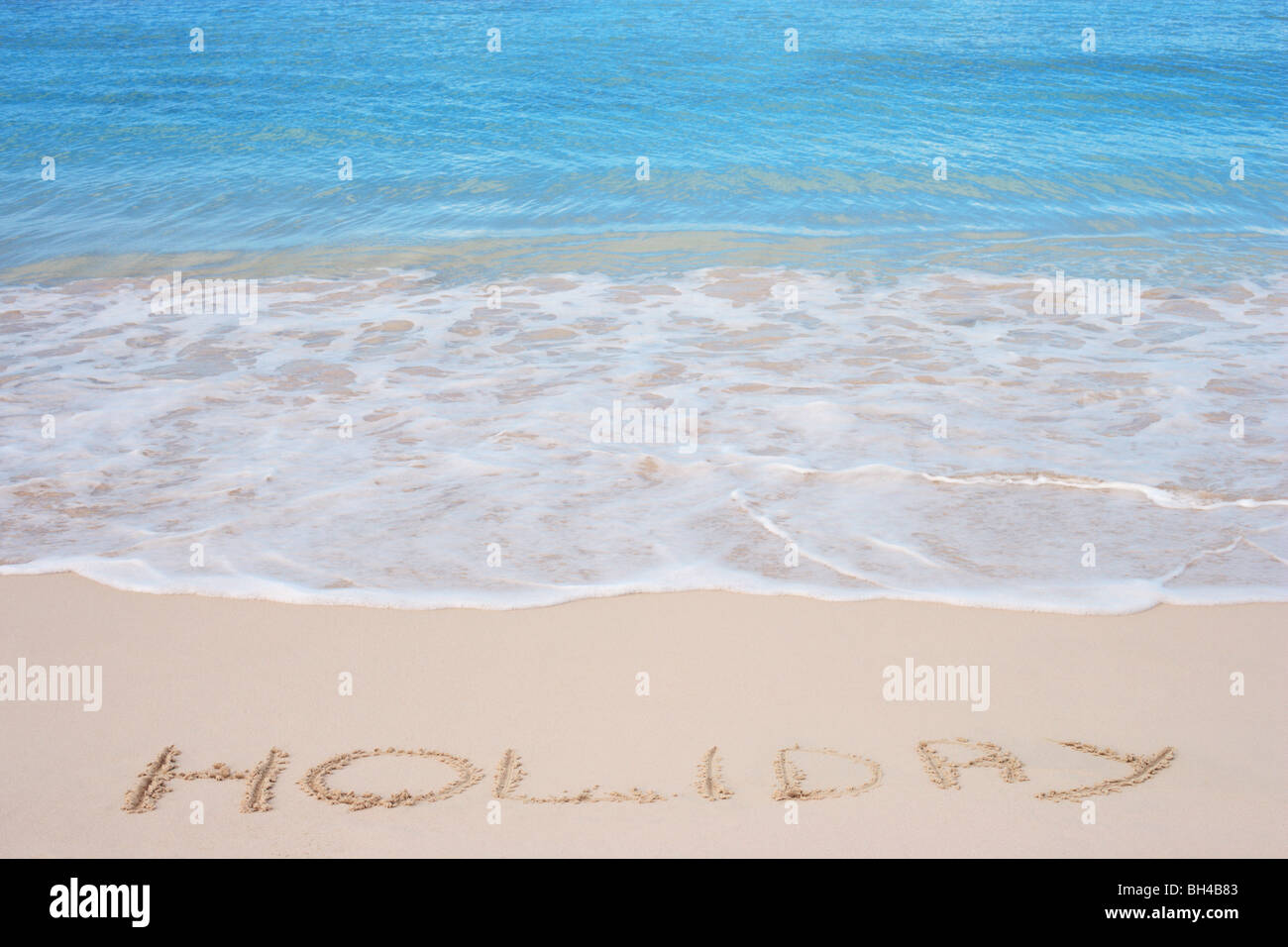 The word 'Holiday' written in the sand on a tropical beach Stock Photo ...