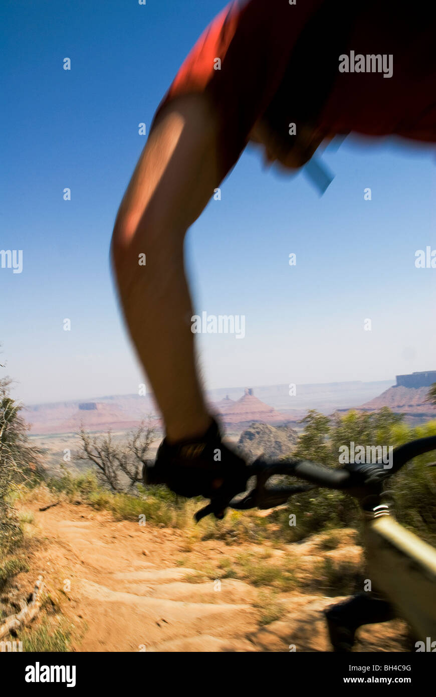 A view over the handlebars of a young man riding a mountain bike down a ...