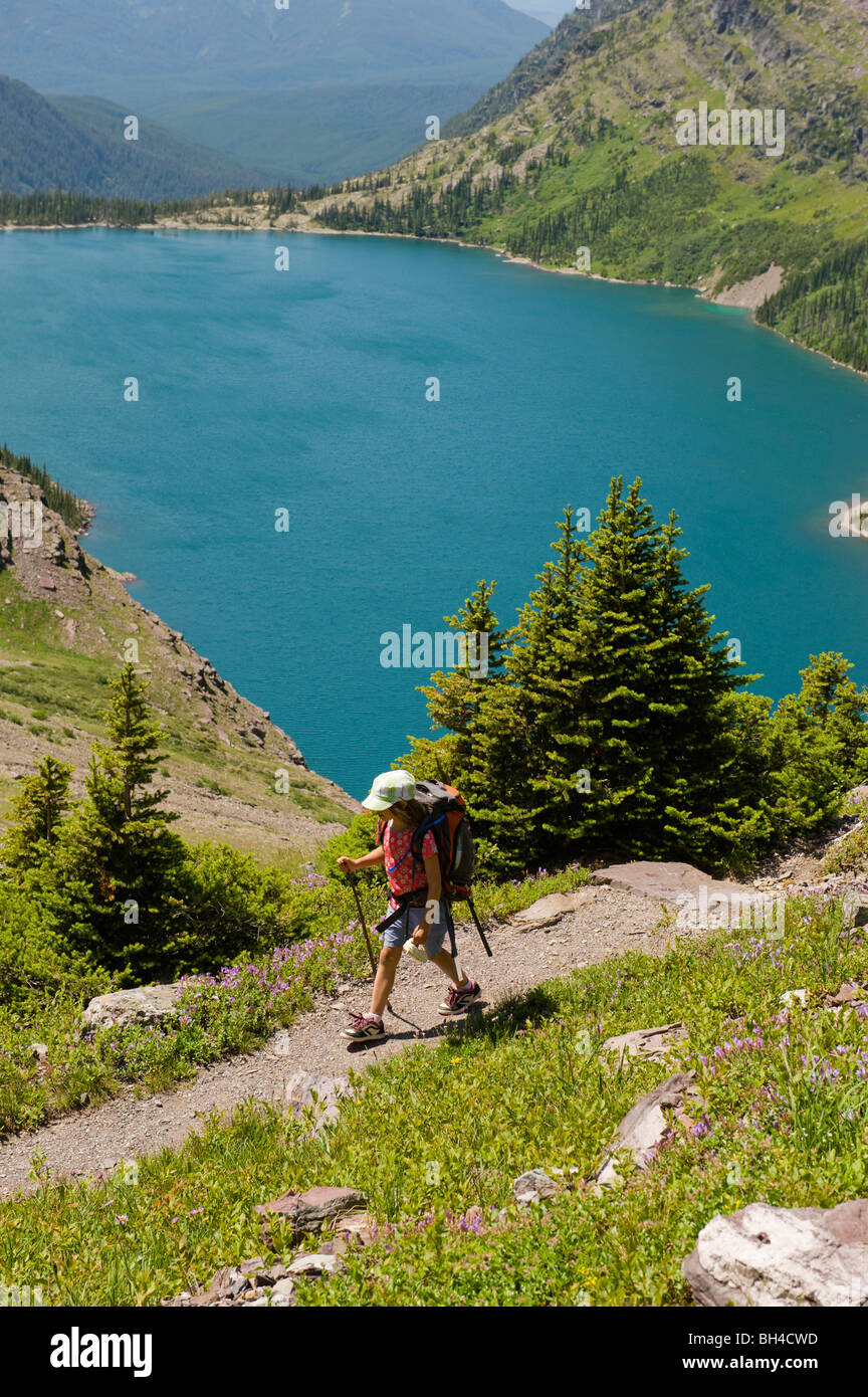 A young girl hikes a trail overlooking a alpine lake in Glacier ...