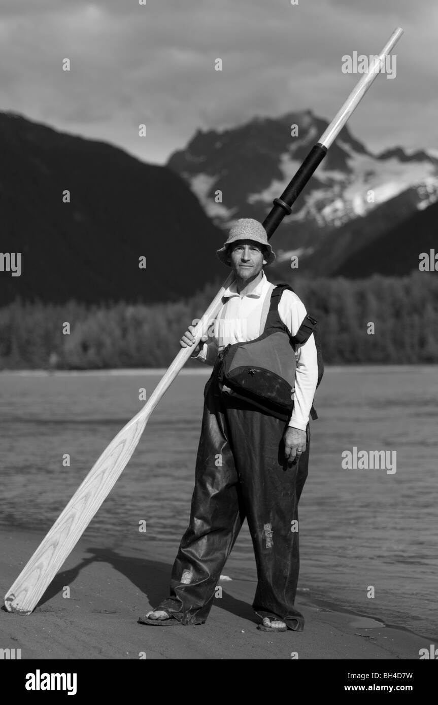 A man stands on the shores of a river for a portrait with an oar, wool ...
