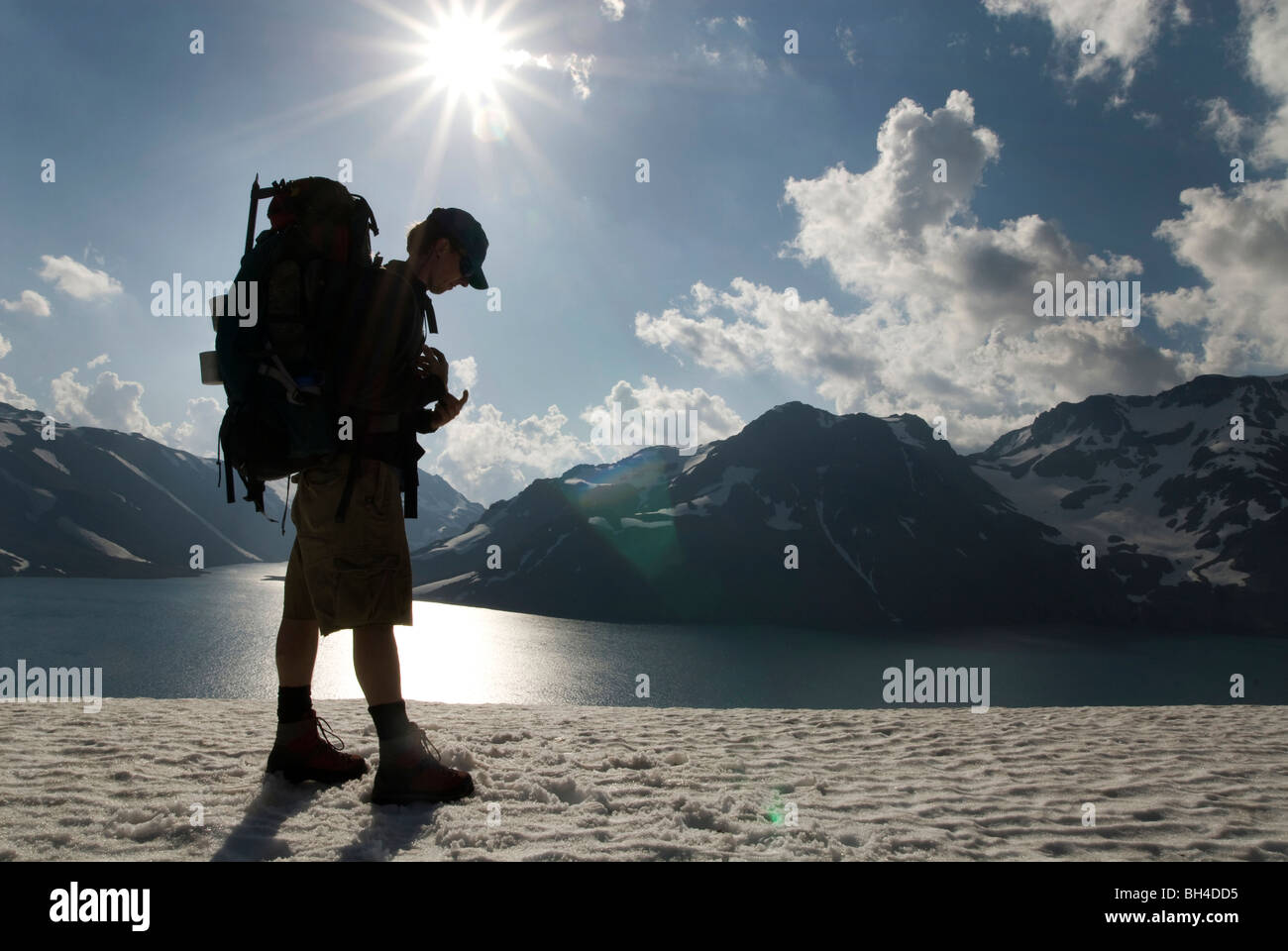 A backpacker stands silhouetted against a dramatic background of the ...