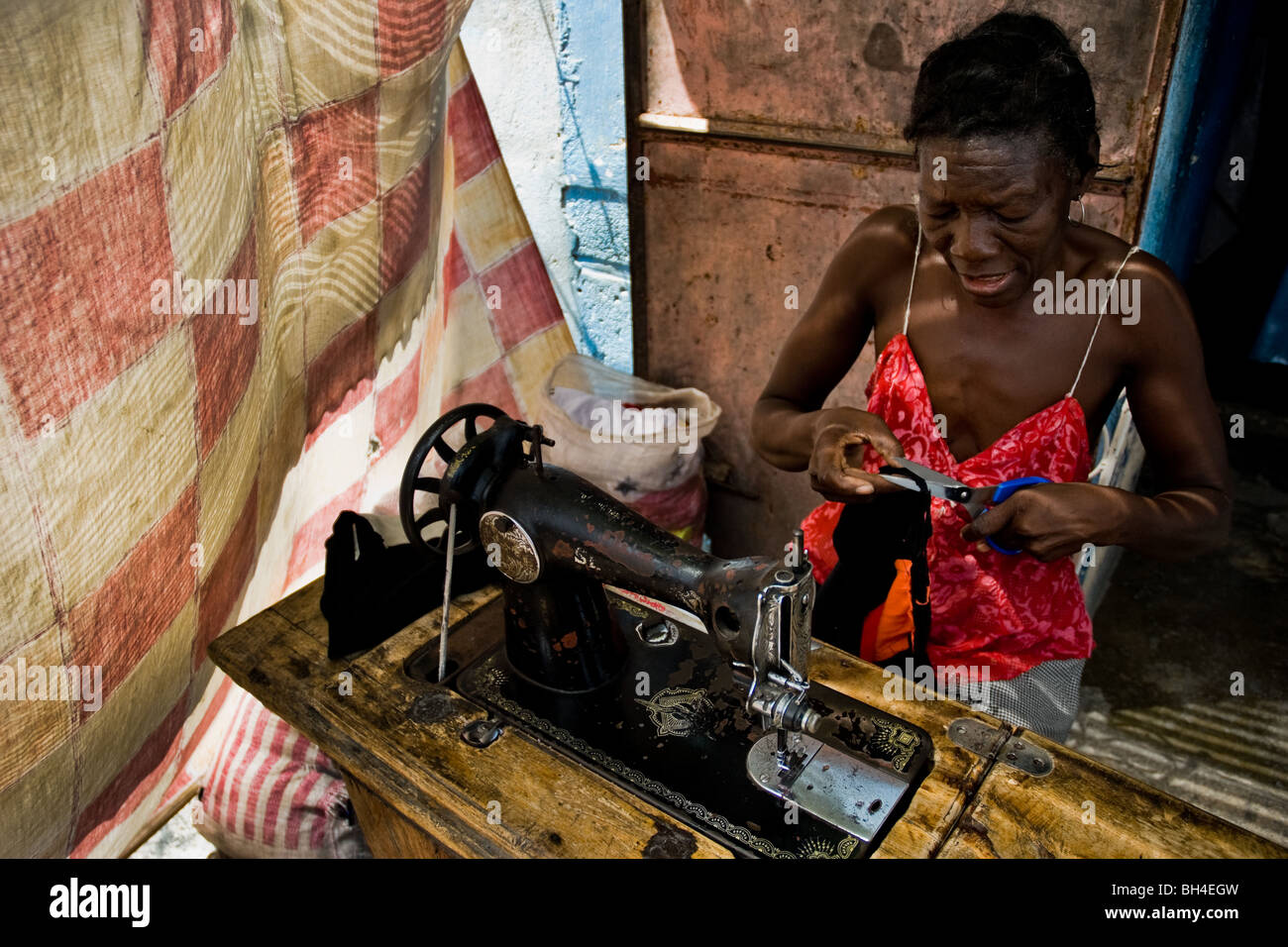A Haitian dressmaker working in front of the house in the slum of Cité ...