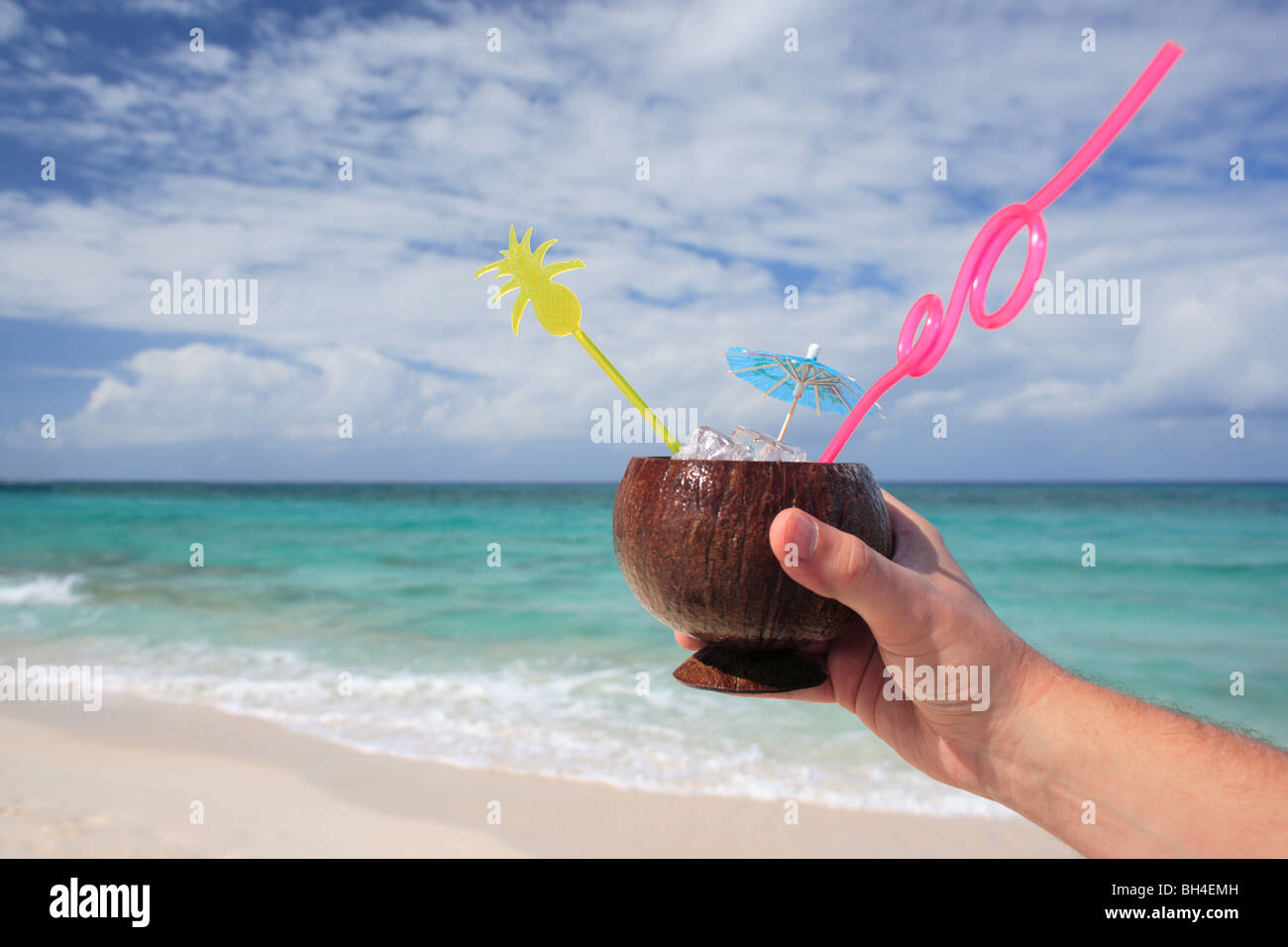 A man's hand holding a tropical cocktail in a coconut shell on a ...