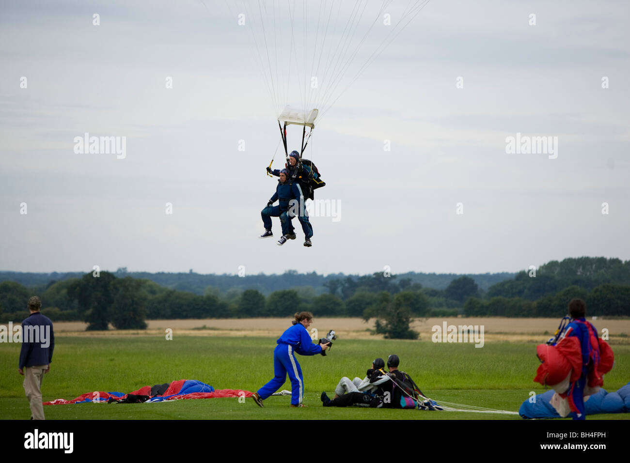 Two people in tandem parachute preparing for landing Stock Photo - Alamy