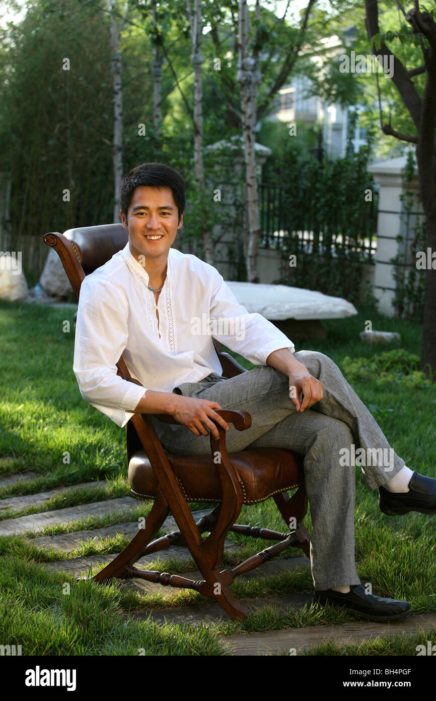 Chinese young man sitting in chair Stock Photo - Alamy
