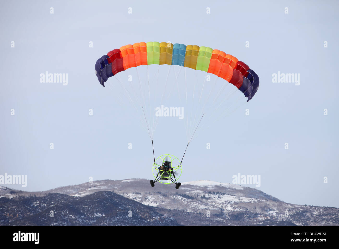 Powered parachute flying over ice and snow covered lake in winter ...